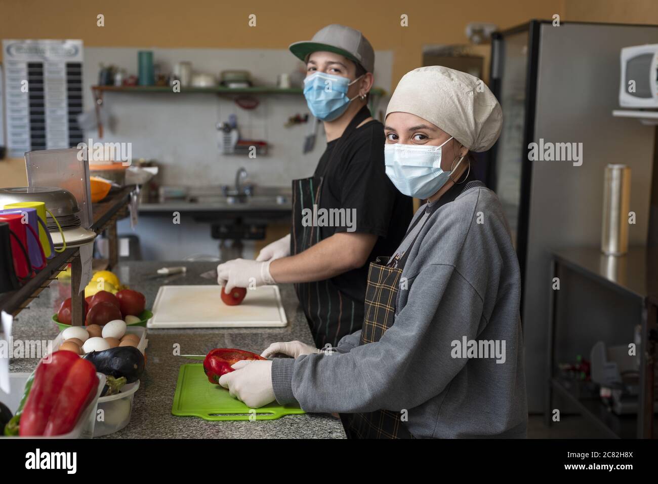Hispanic chefs cooking in the kitchen wearing protective medical face ...