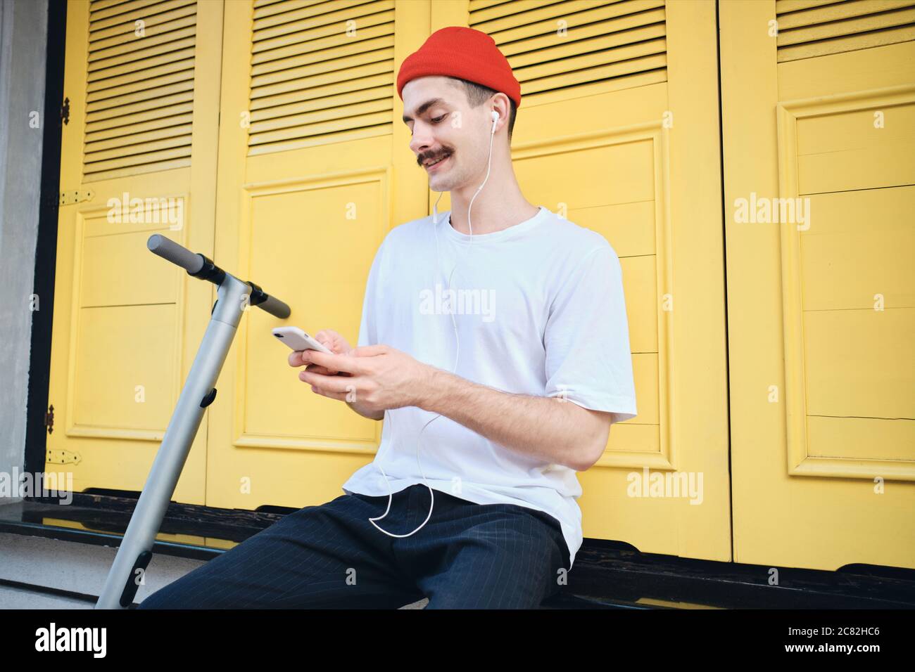 Young smiling mustache man in T-shirt and red hat sitting with e ...