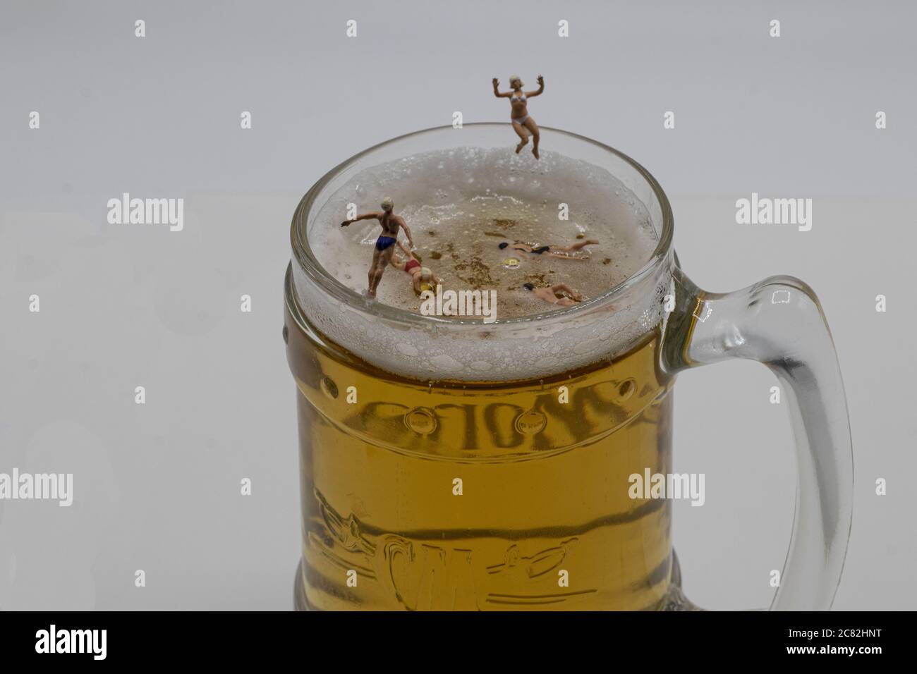 Unique scale model of miniature characters swimming in beer on a white ...