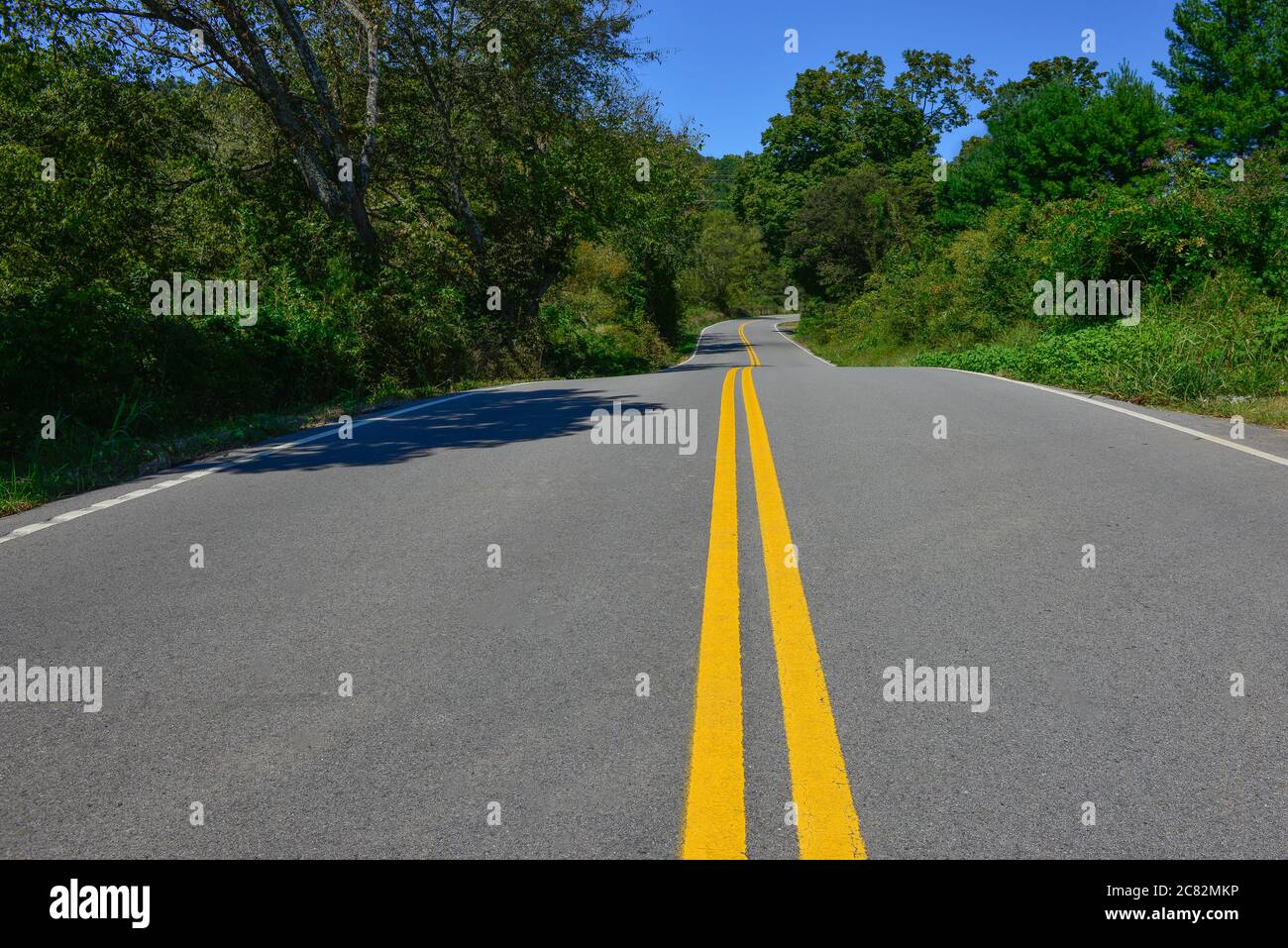 A low angle view from the middle of the yellow striped country highway ...