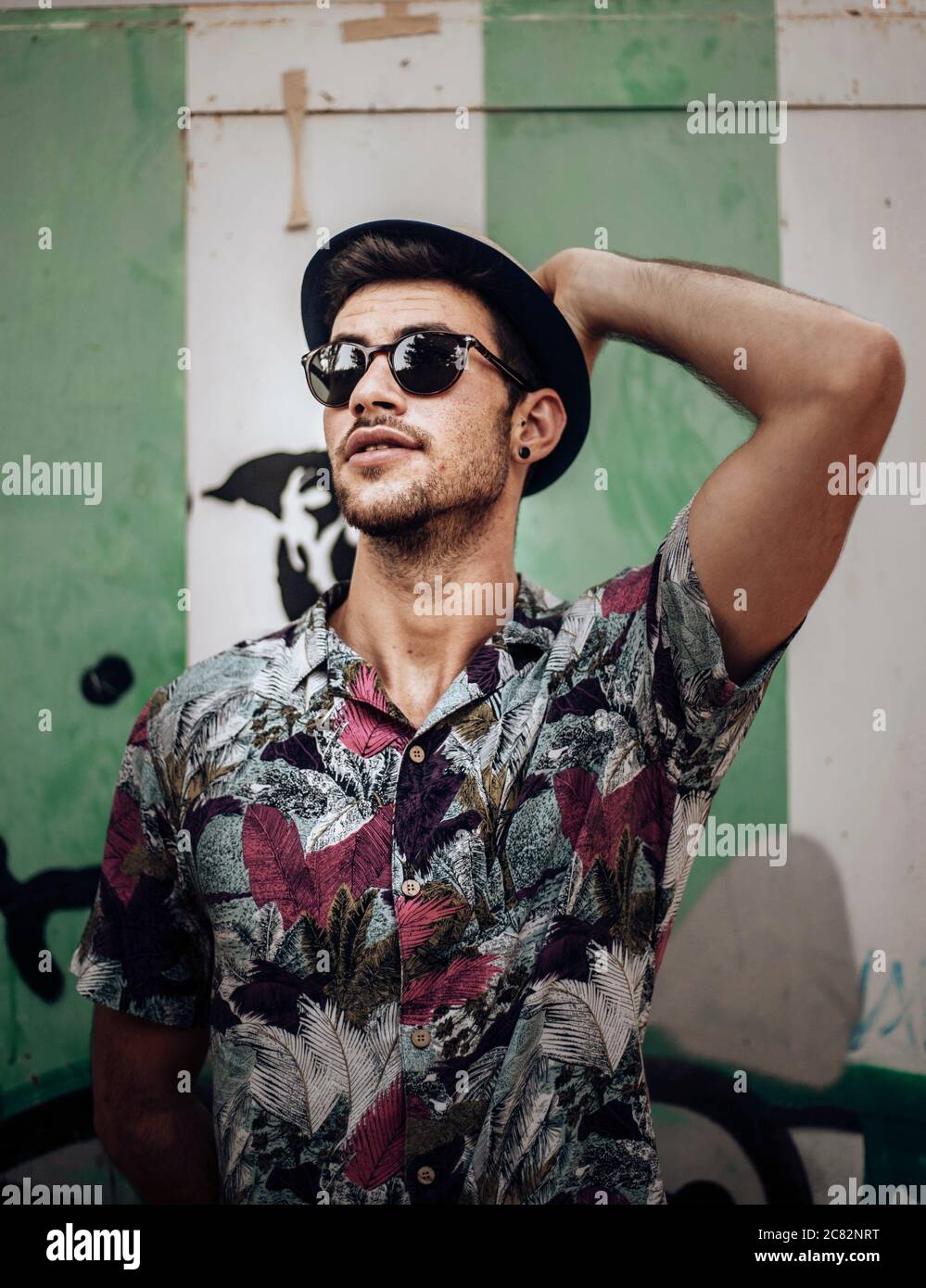 Handsome young guy with sunglasses with his hand in his hat Stock Photo ...
