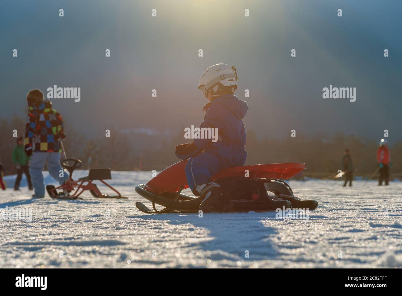 child comes down from the mountain riding a red sled in winter Stock ...