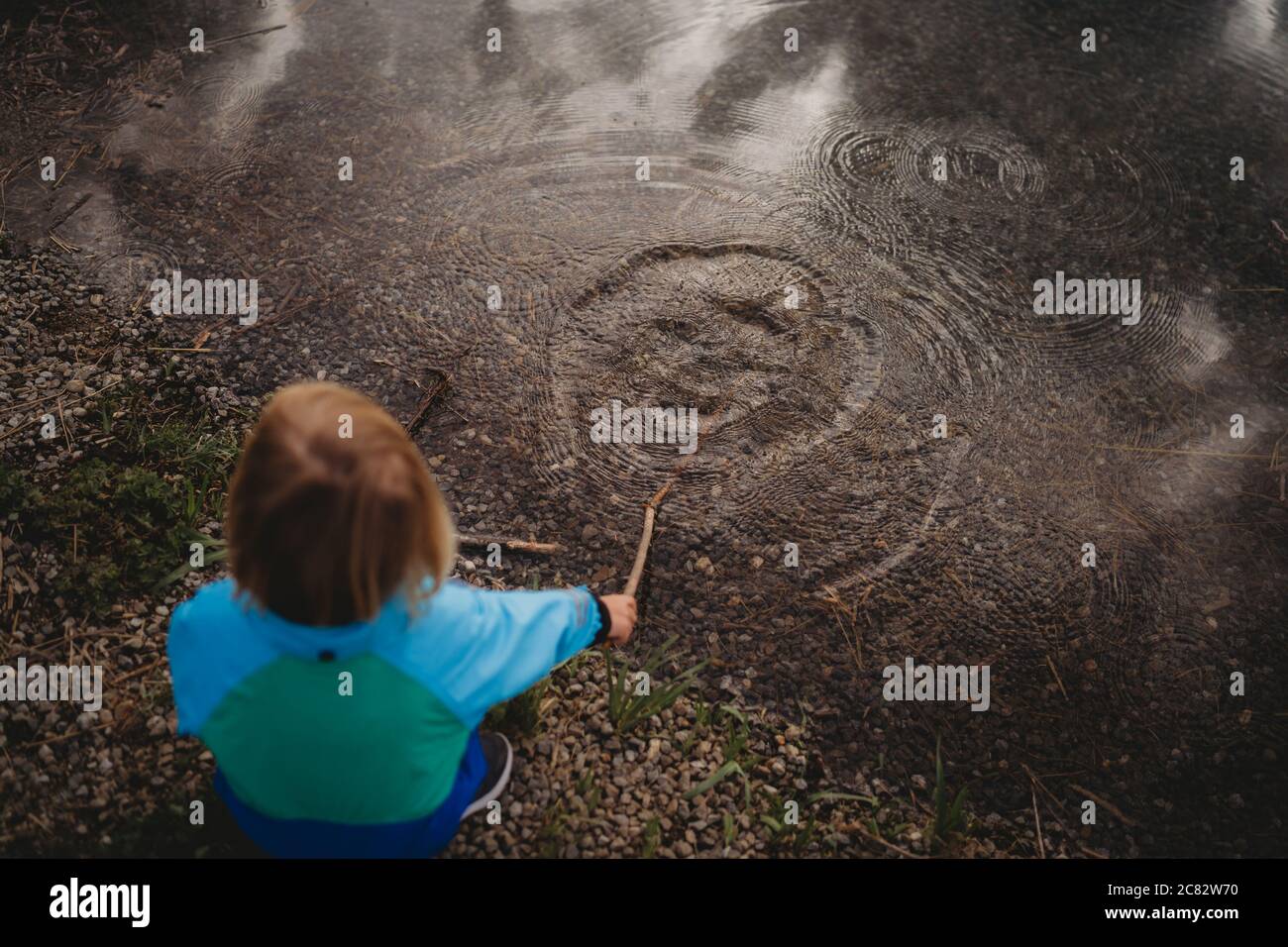 Back view of child playing with water rings at the lake in a park Stock ...