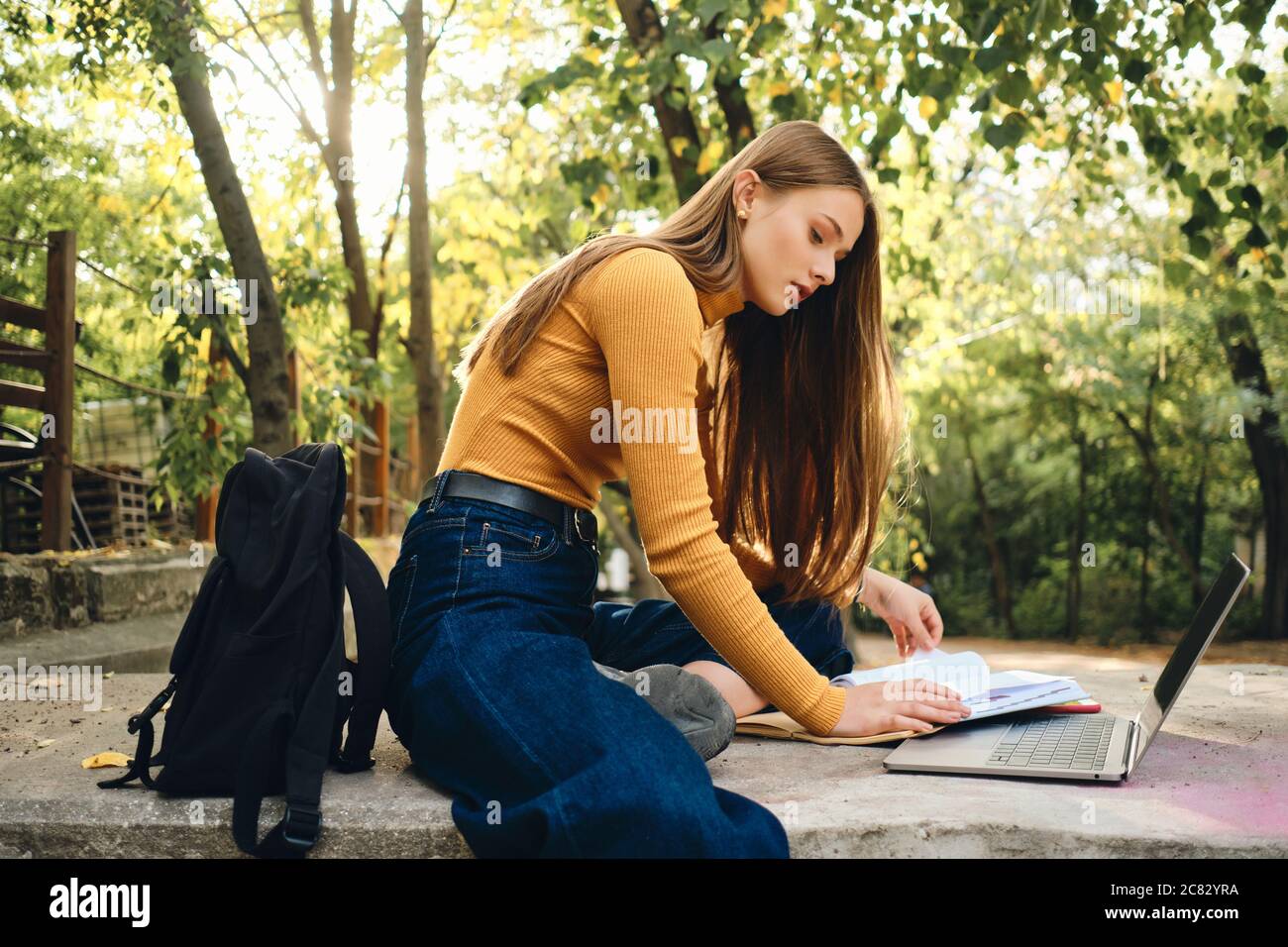 Side view of attractive student girl studying with laptop and book in ...