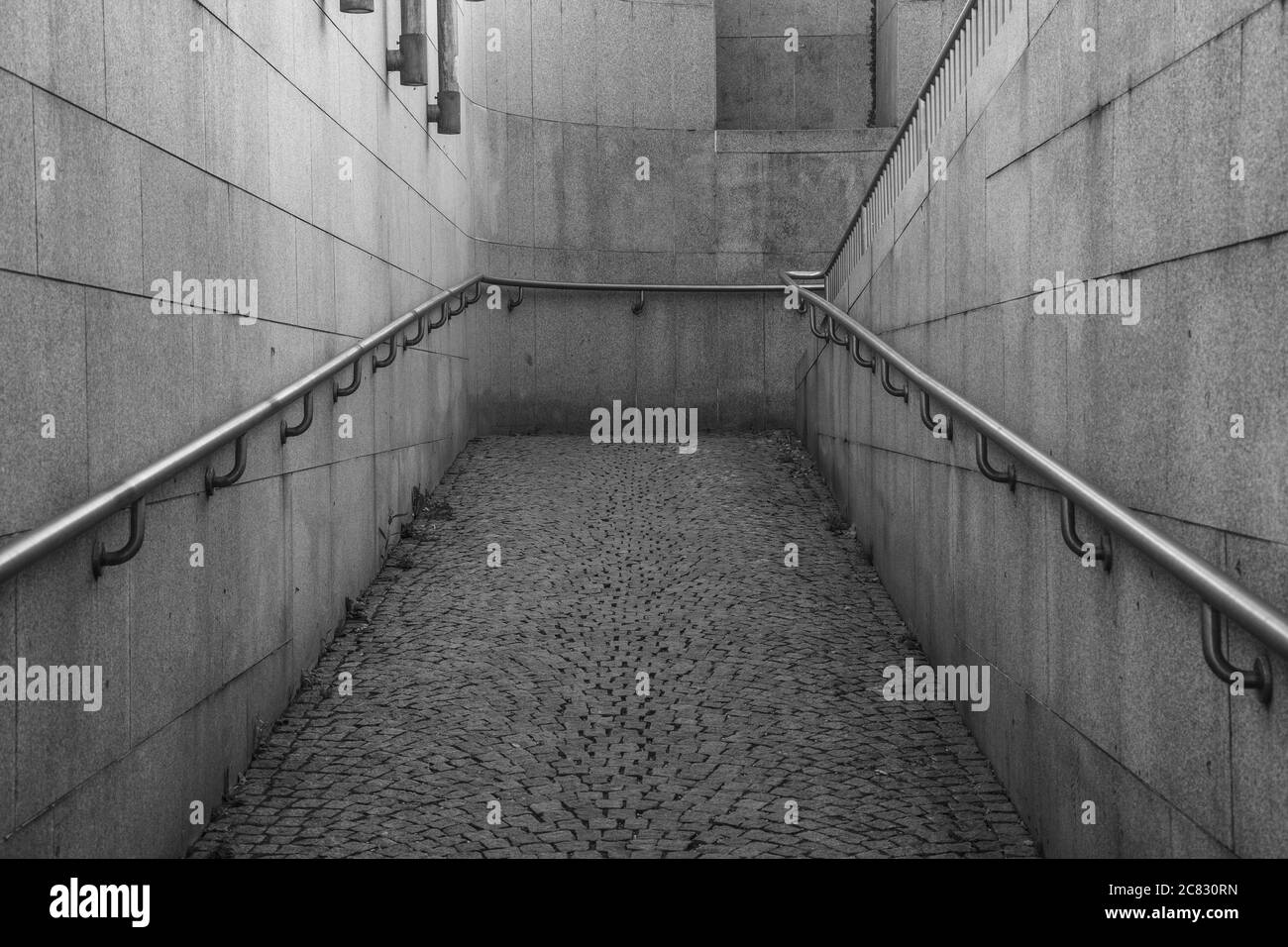 Greyscale shot of a wheelchair ramp by a building captured during the ...
