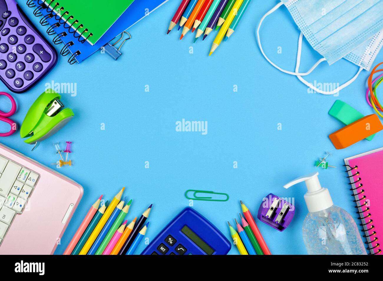School supplies and COVID 19 prevention items. Frame on a blue paper ...