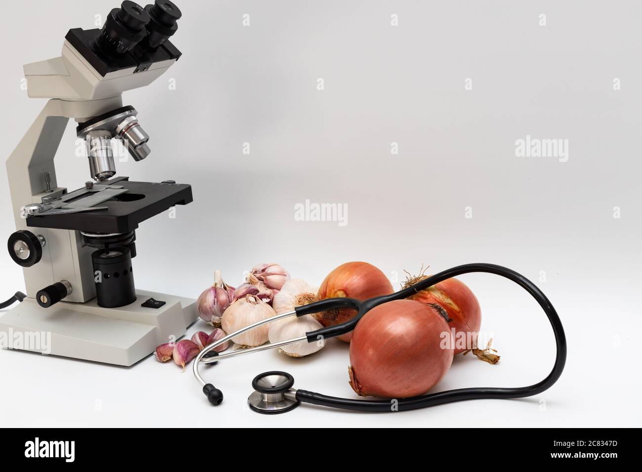 Microscope next to garlic, onions and phonendoscope on a white ...