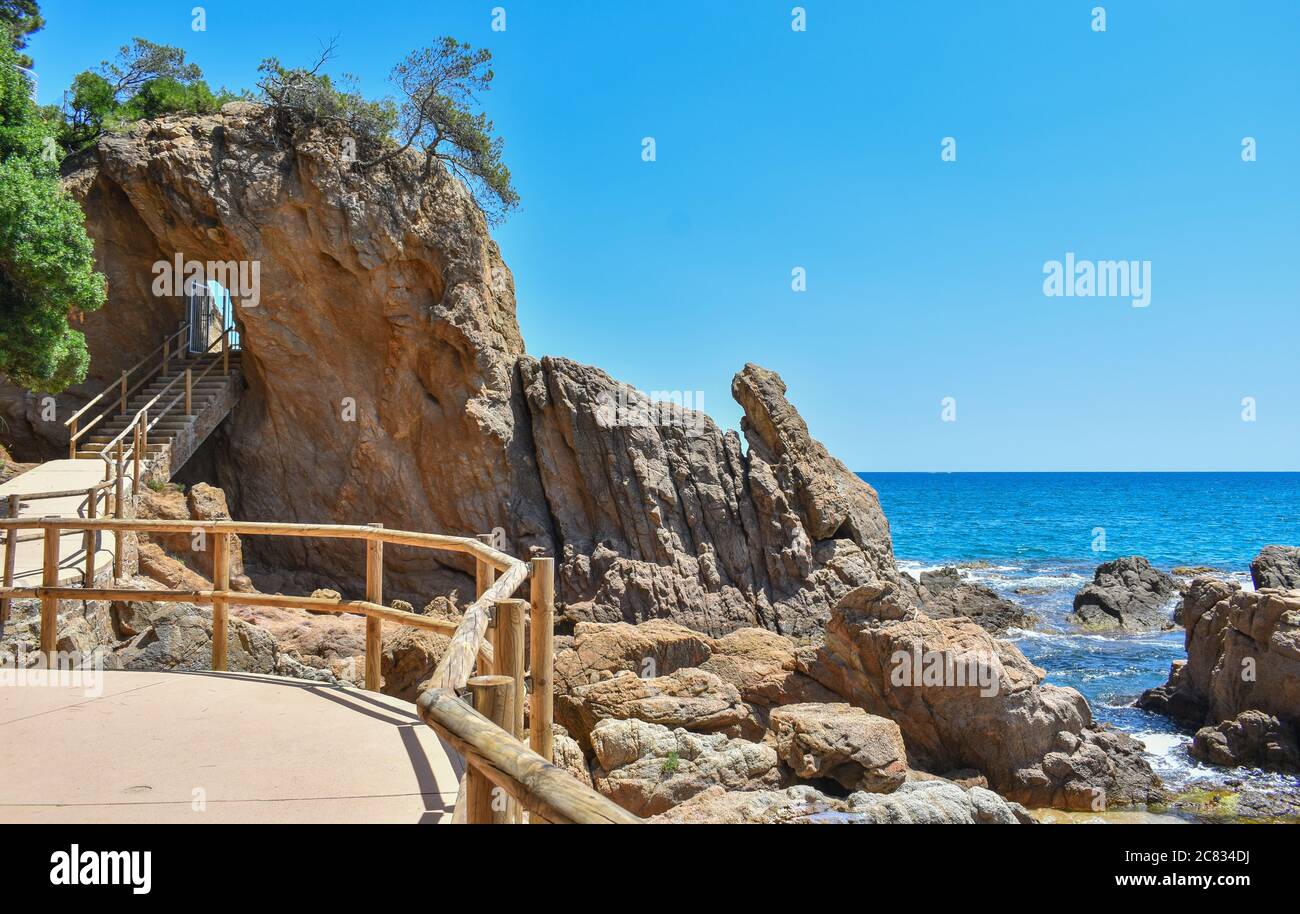 Staircase in a cliff surrounded by handrails and the sea under a blue ...