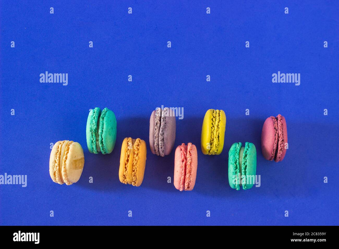 Overhead shot of rows of colorful macarons on a blue background Stock ...