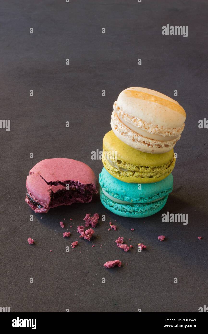 Vertical closeup shot of a stack of colorful macarons and crumbs on a ...