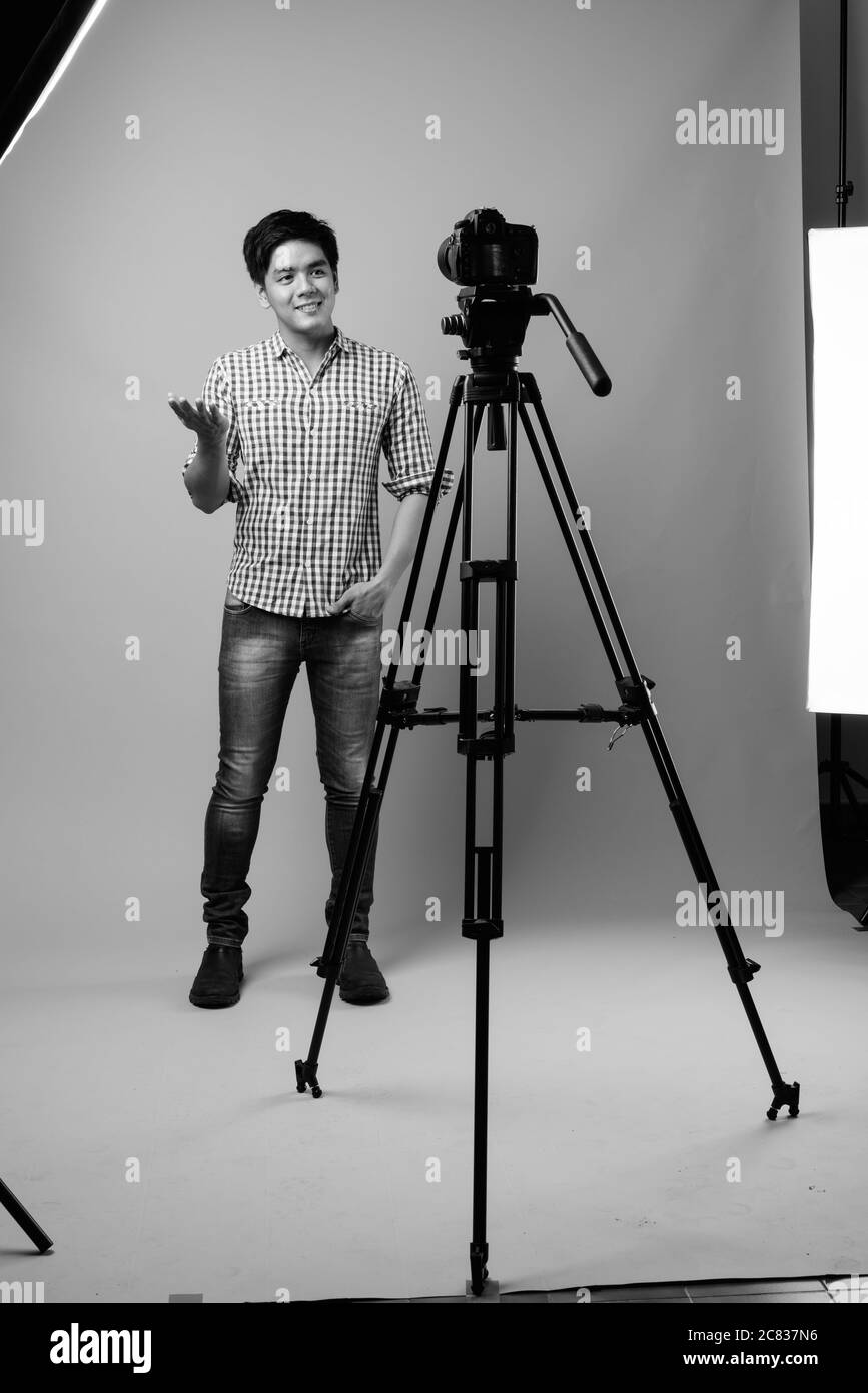 Portrait of young handsome Filipino hipster man vlogging with camera ...