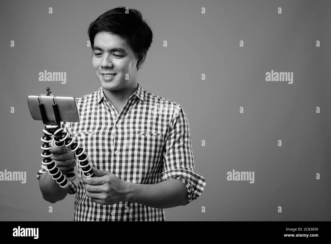 Portrait of young handsome Filipino hipster man vlogging with phone ...