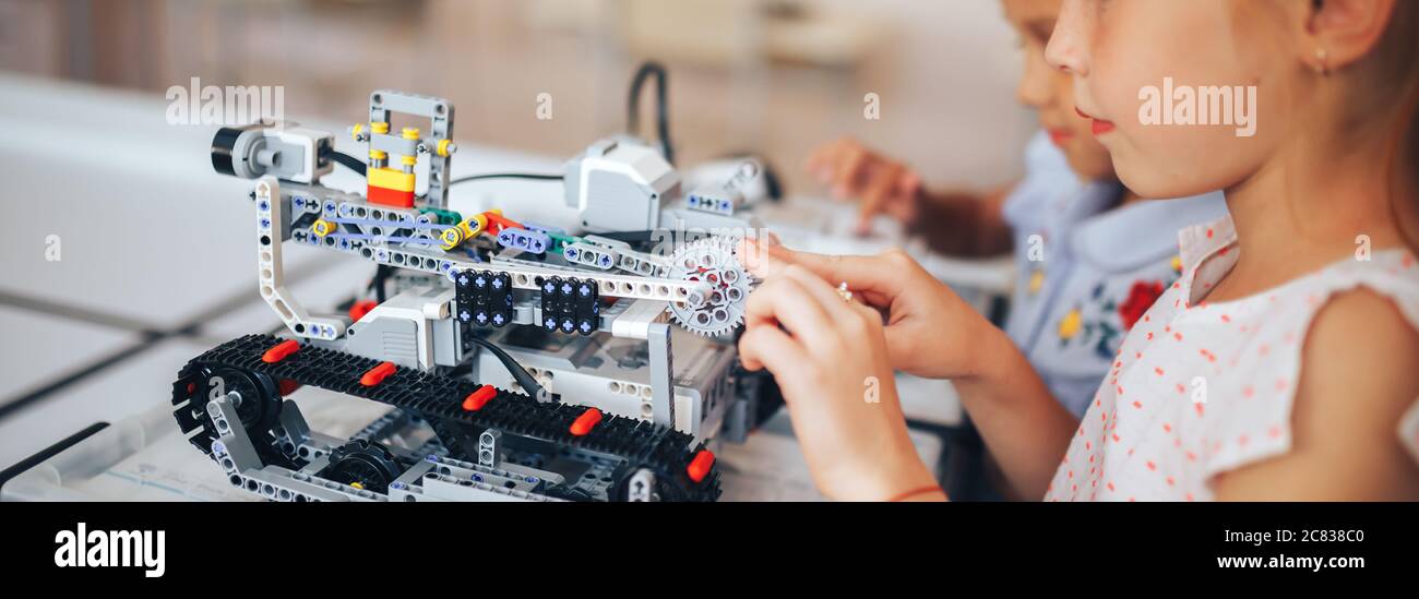 Two schoolgirls study in a robotics class, assemble a robot constructor ...