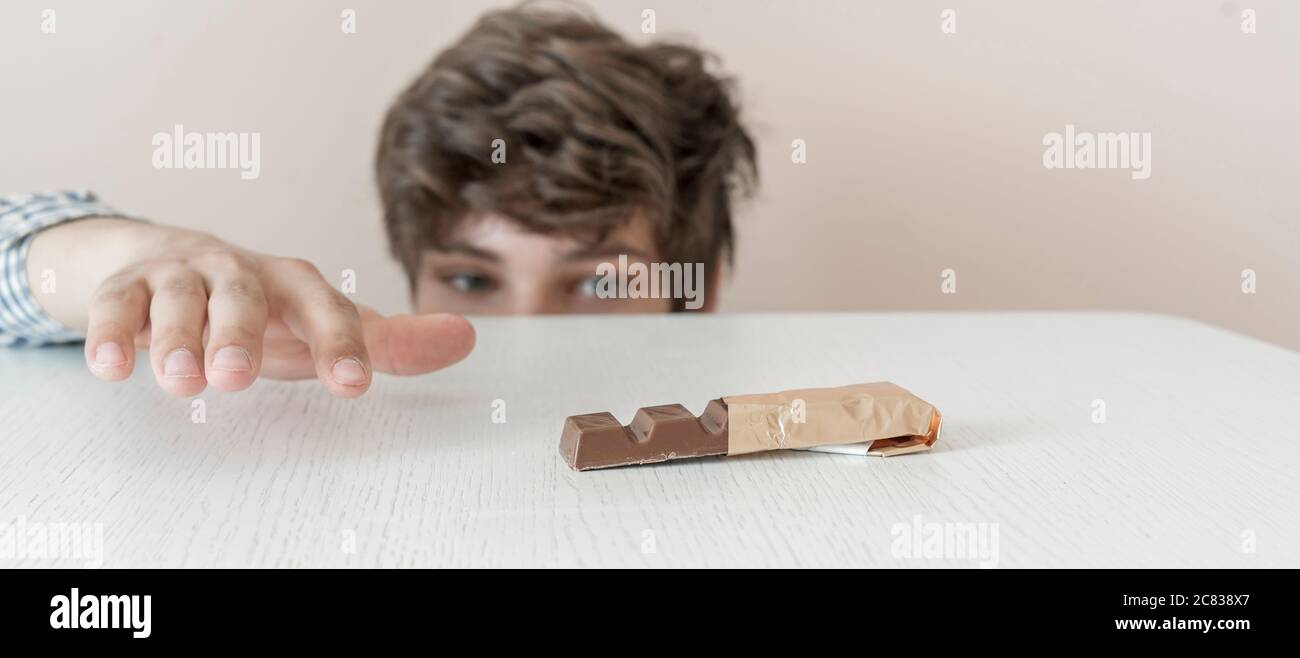 the male teenager face eyes above the table picking snatching the sweet ...