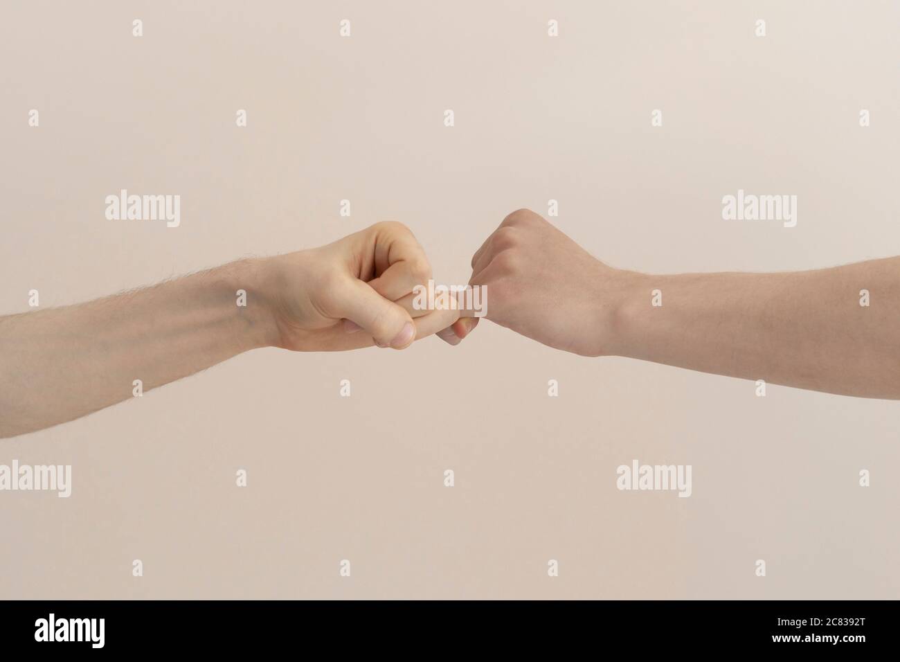a close up two people hook little fingers of each other, isolated ...