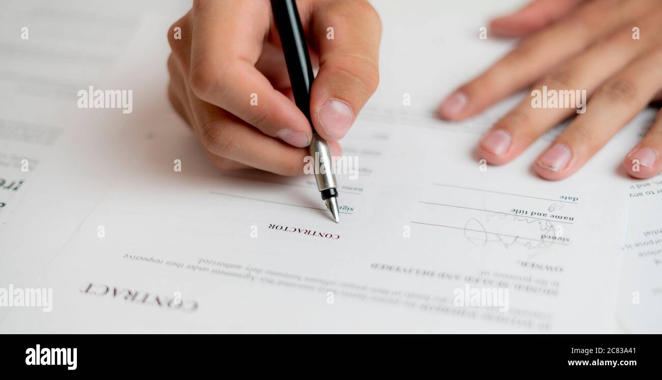 a person's hand holding a pen and sign the document contract in office ...