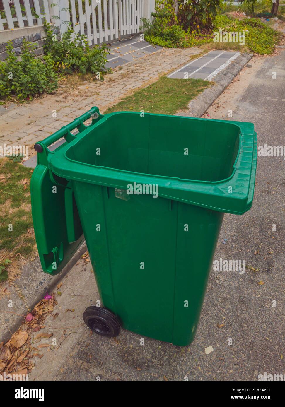 Opened big empty green plastic trash garbage bin in front of the modern ...