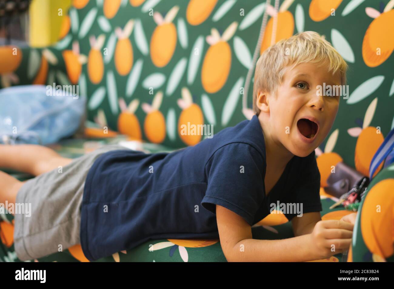 Cute noisy boy scream very loud in a temper tantrum liying on sofa ...