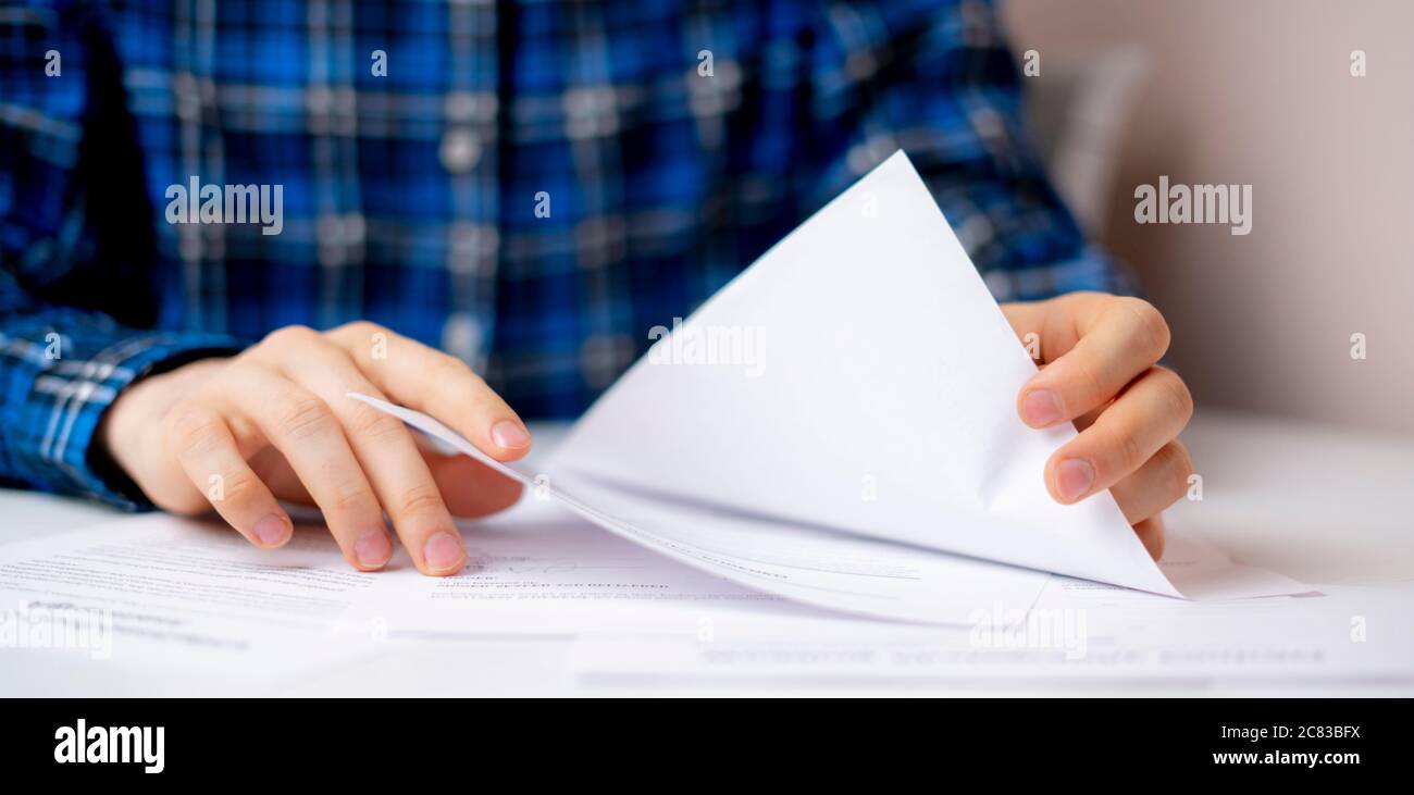 a hand holding a document sheet, doing some paper work in the office ...