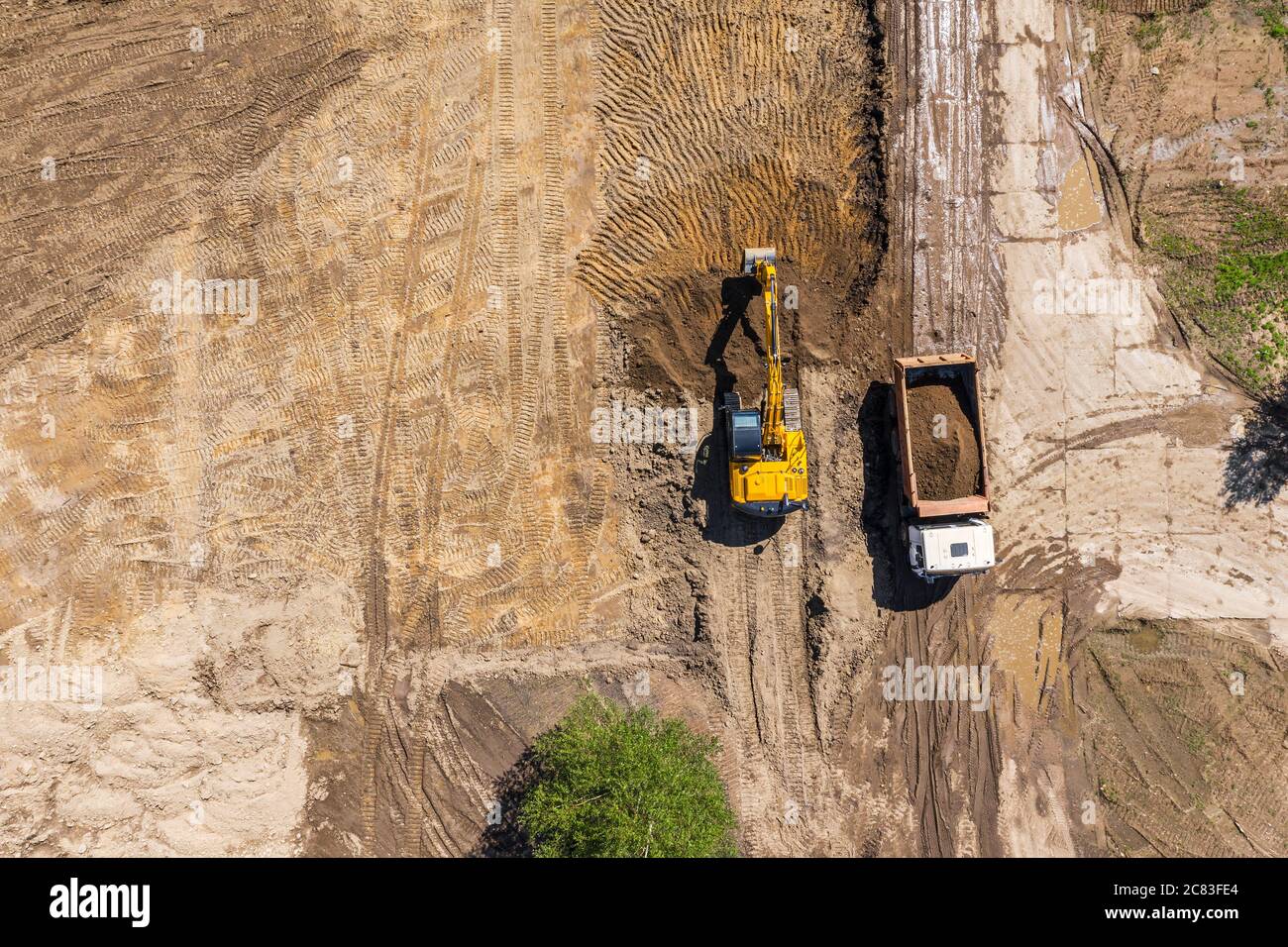 aerial view of excavator loading sand into dump truck on construction site. industrial area top ...