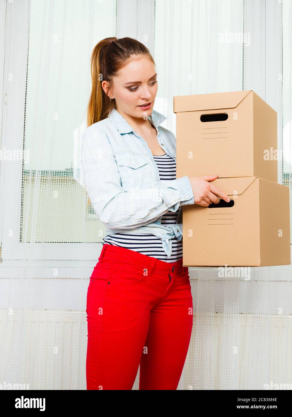 Woman moving in carrying cartons boxes. Young girl unpacking at new ...