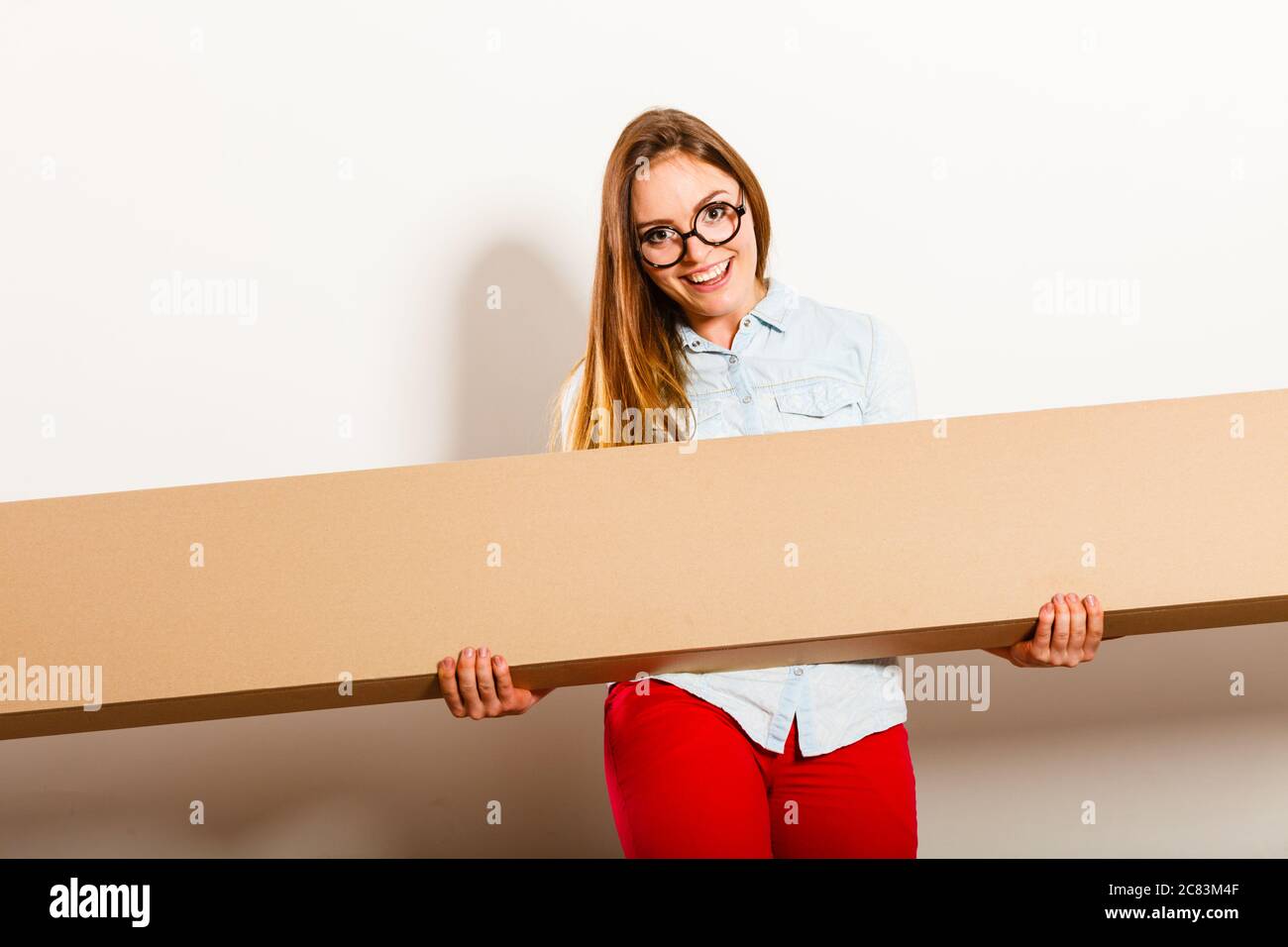 Happy woman moving into new apartment house carrying carton box with ...