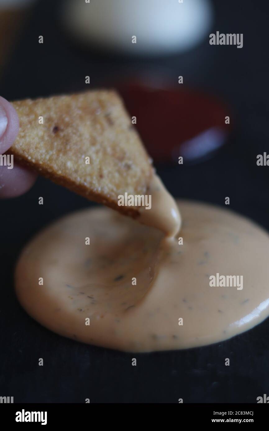 Vertical shot of a man dipping chips into a sauce Stock Photo - Alamy