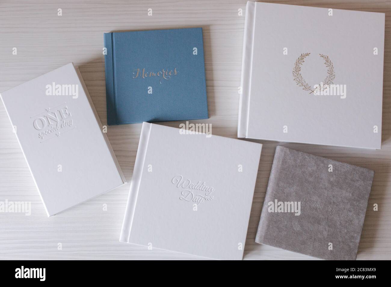 Different photobooks and photoboxes on white wooden table. Textile and ...