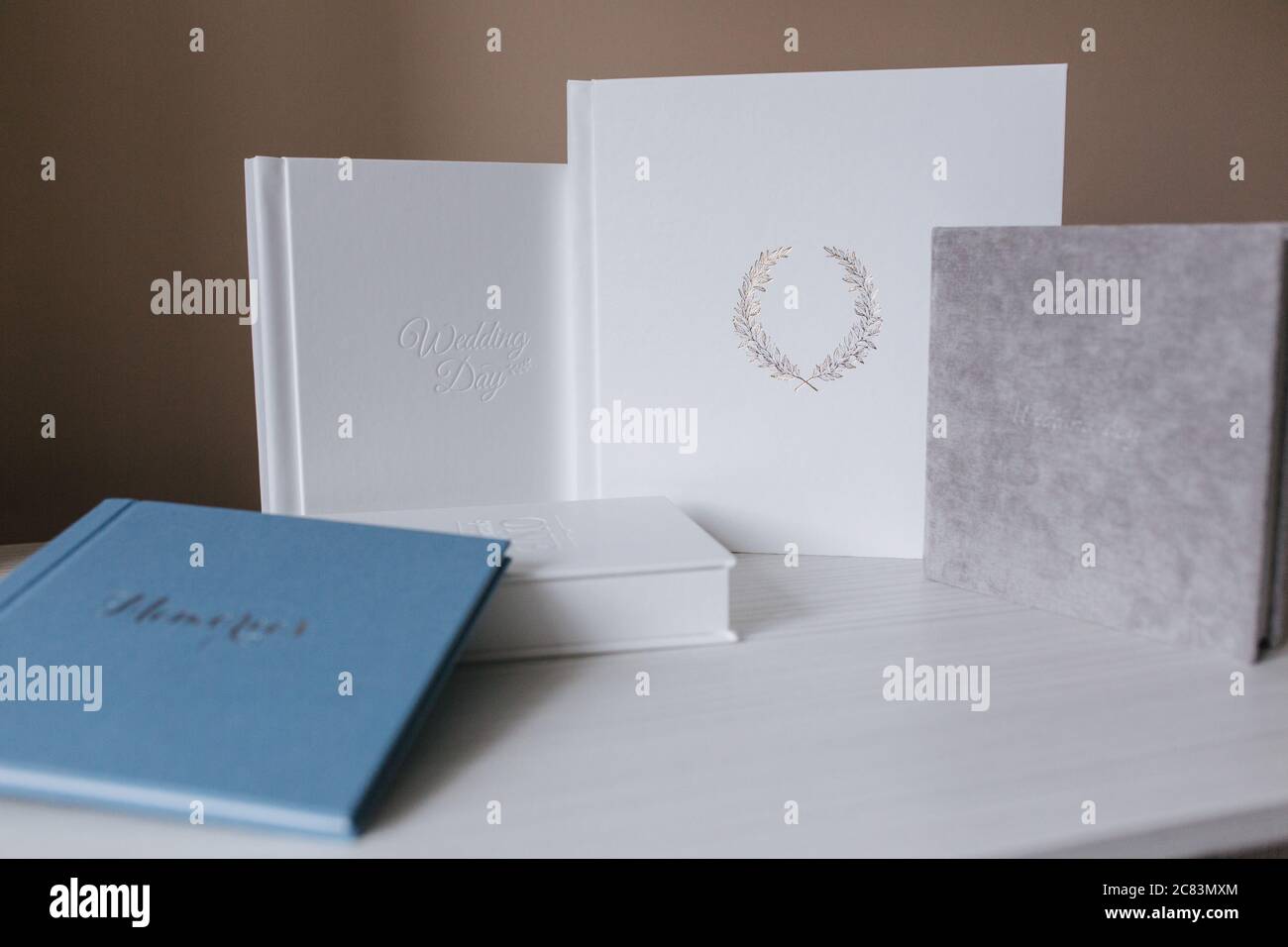 Different photobooks and photoboxes on white wooden table. Textile and ...