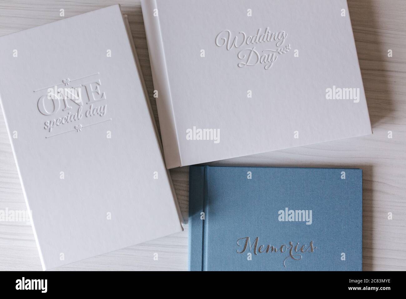 Different photobooks and photoboxes on white wooden table. Textile and ...