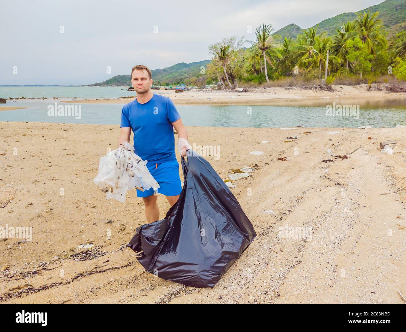Man in gloves pick up plastic bags that pollute sea. Problem of spilled ...