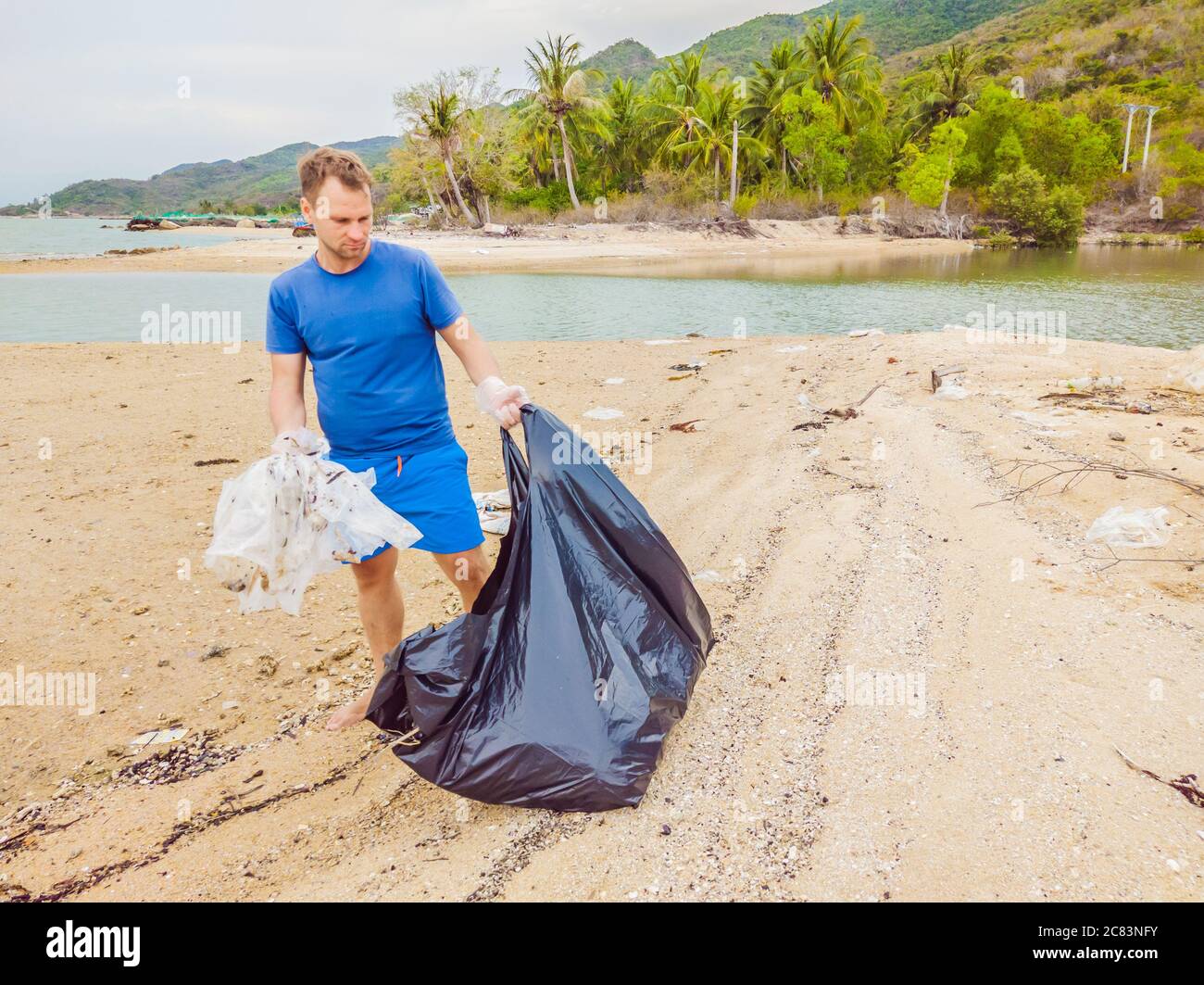 Man in gloves pick up plastic bags that pollute sea. Problem of spilled ...