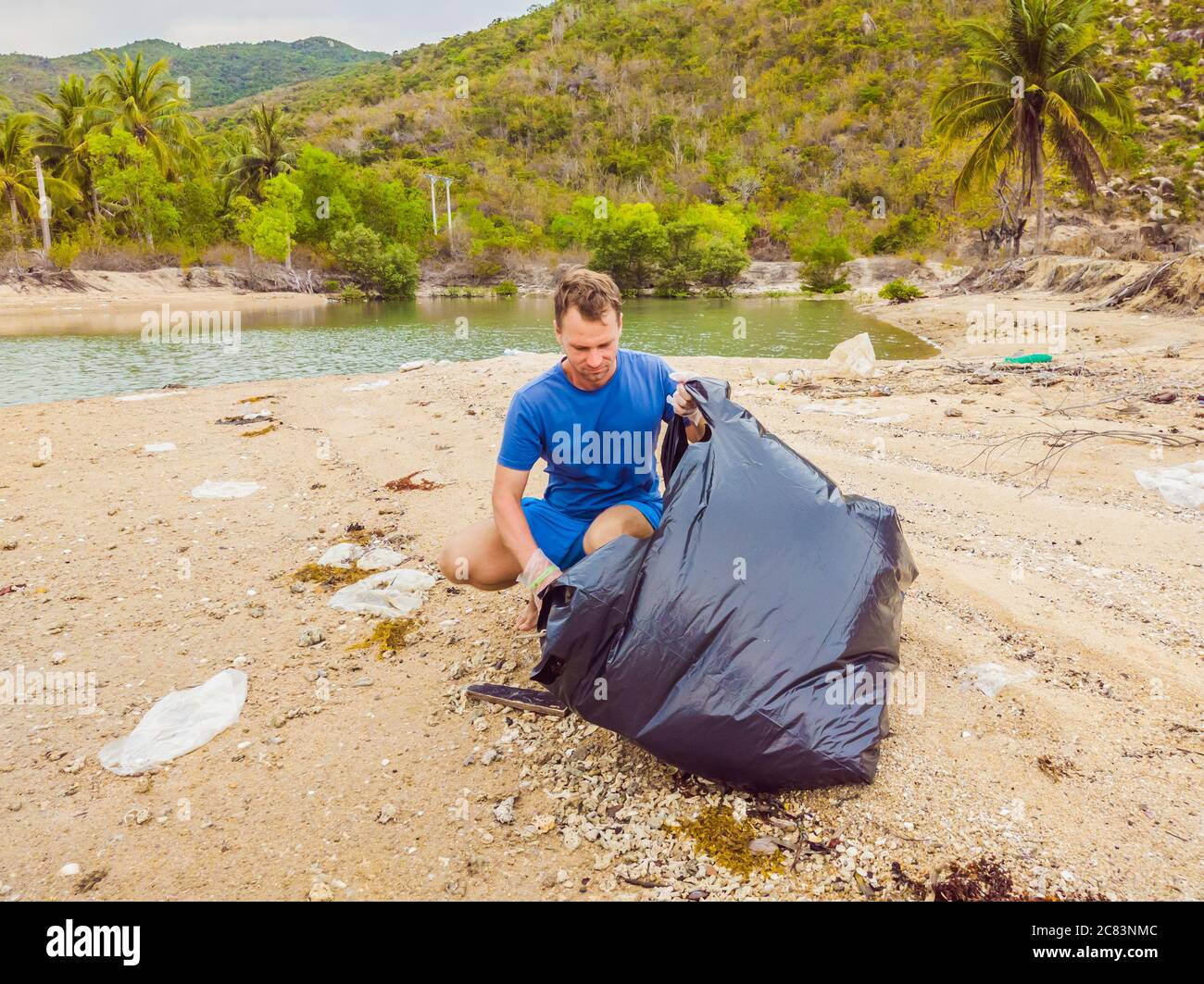 Man in gloves pick up plastic bags that pollute sea. Problem of spilled ...