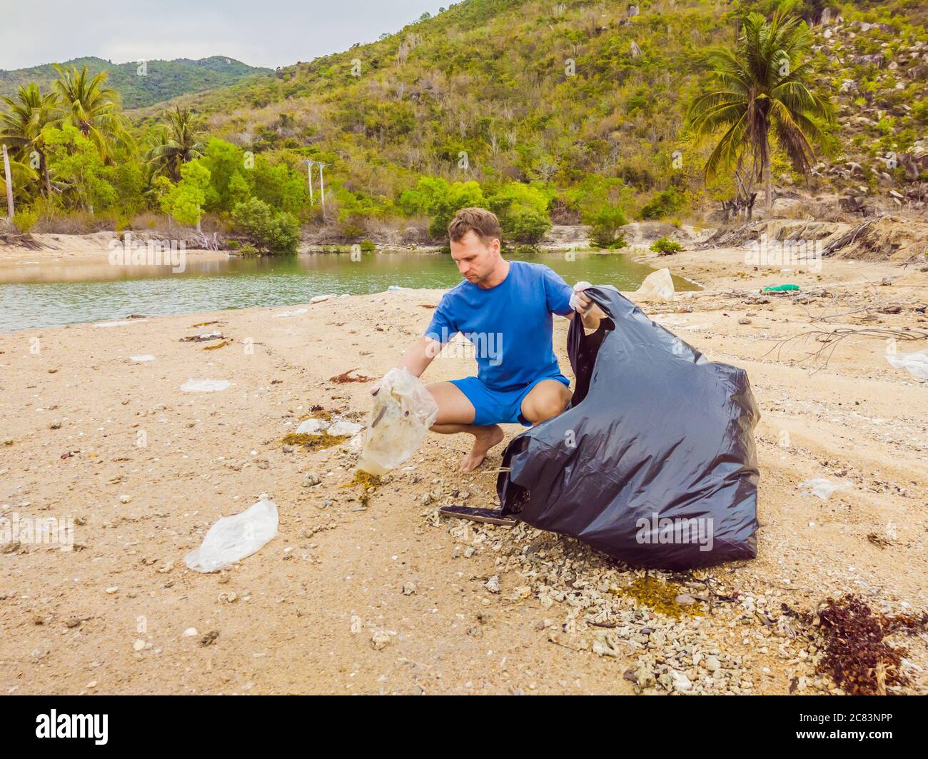 Man in gloves pick up plastic bags that pollute sea. Problem of spilled ...