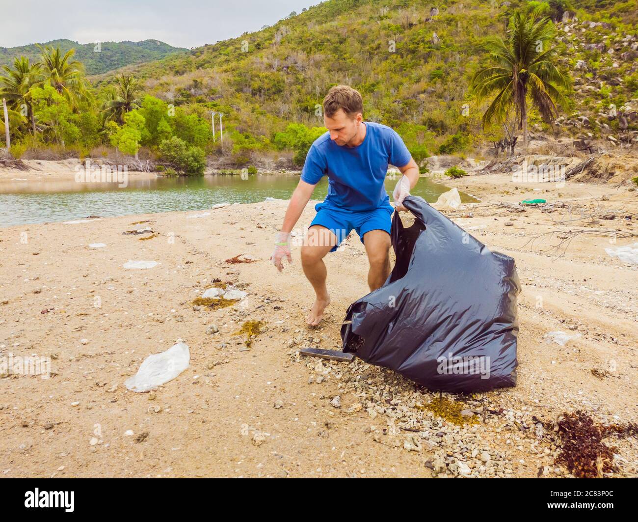 Man in gloves pick up plastic bags that pollute sea. Problem of spilled ...