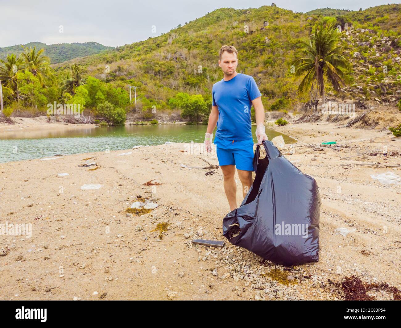 Man in gloves pick up plastic bags that pollute sea. Problem of spilled ...