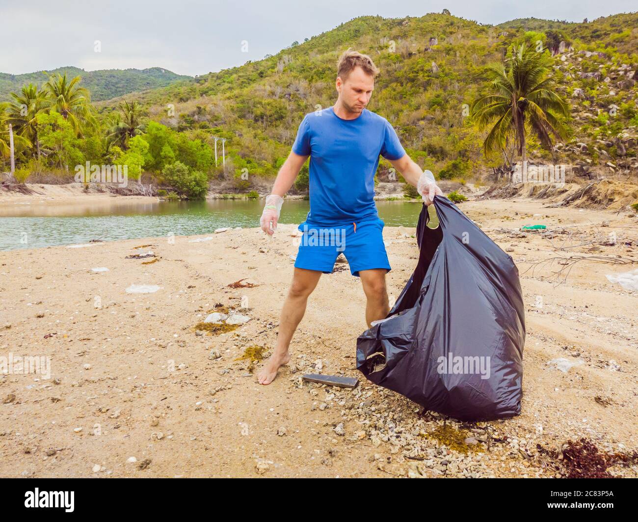 Man in gloves pick up plastic bags that pollute sea. Problem of spilled ...