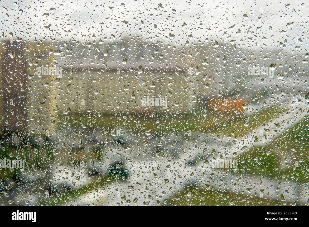 rain splashes fall on a window with a background. drop window a window pane with a blurred ...