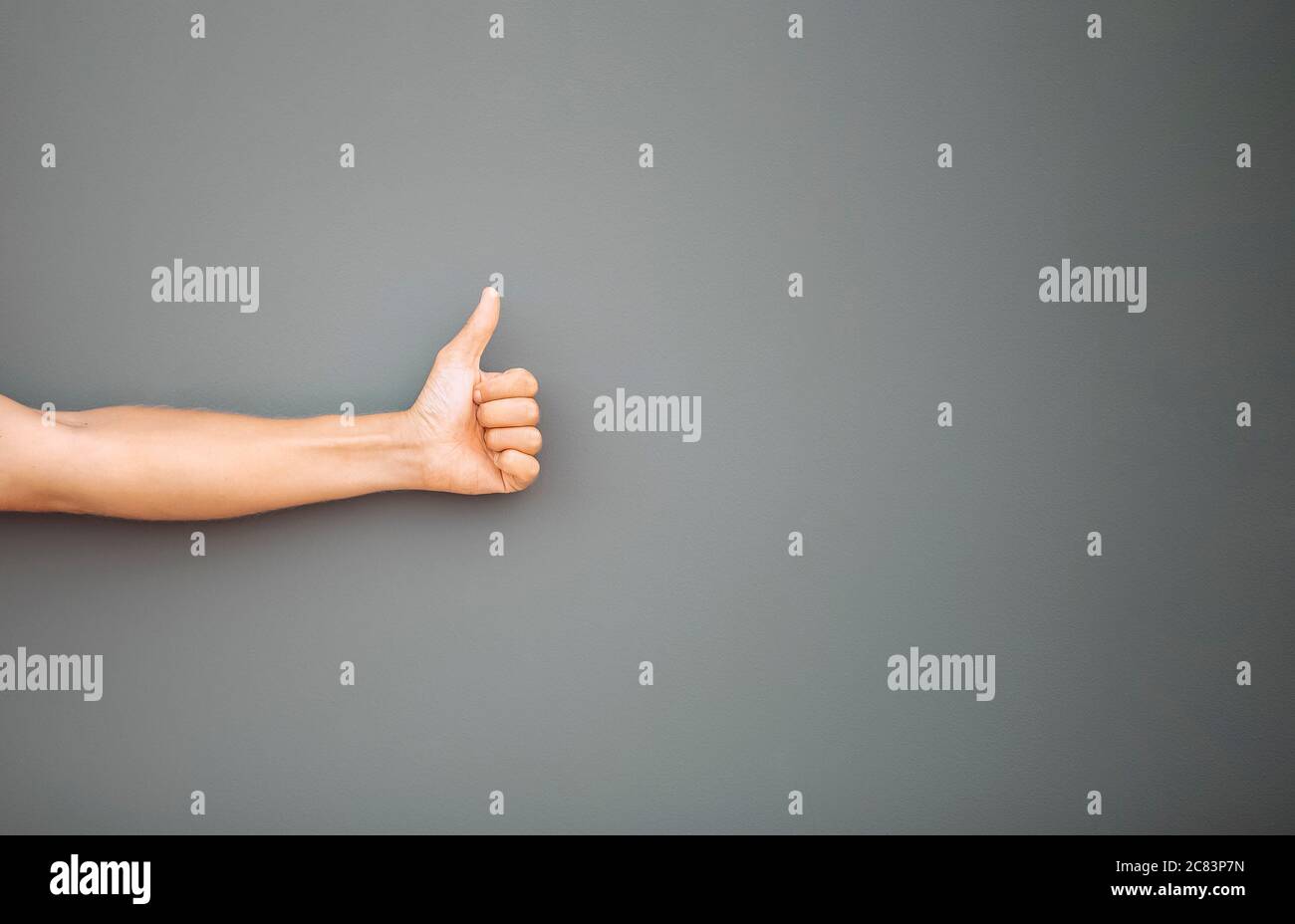 Male left hand giving thumb up like concept isolated on gray background ...