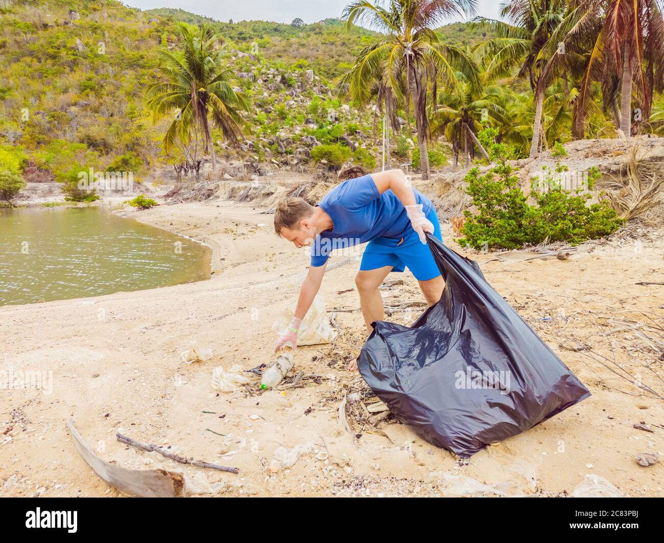 Man in gloves pick up plastic bags that pollute sea. Problem of spilled ...