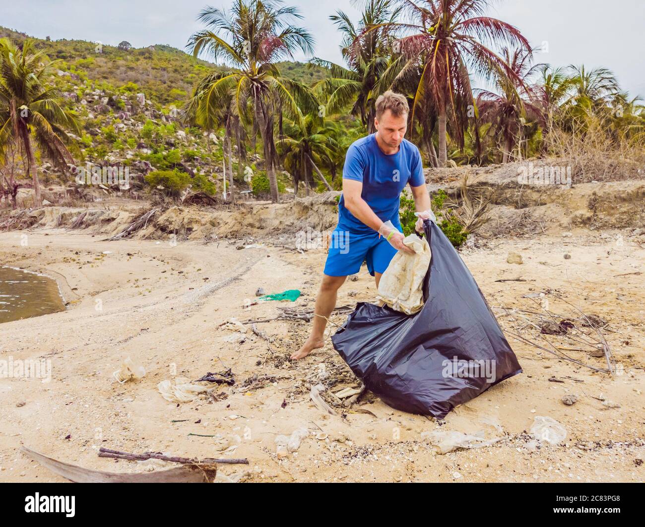 Man in gloves pick up plastic bags that pollute sea. Problem of spilled ...