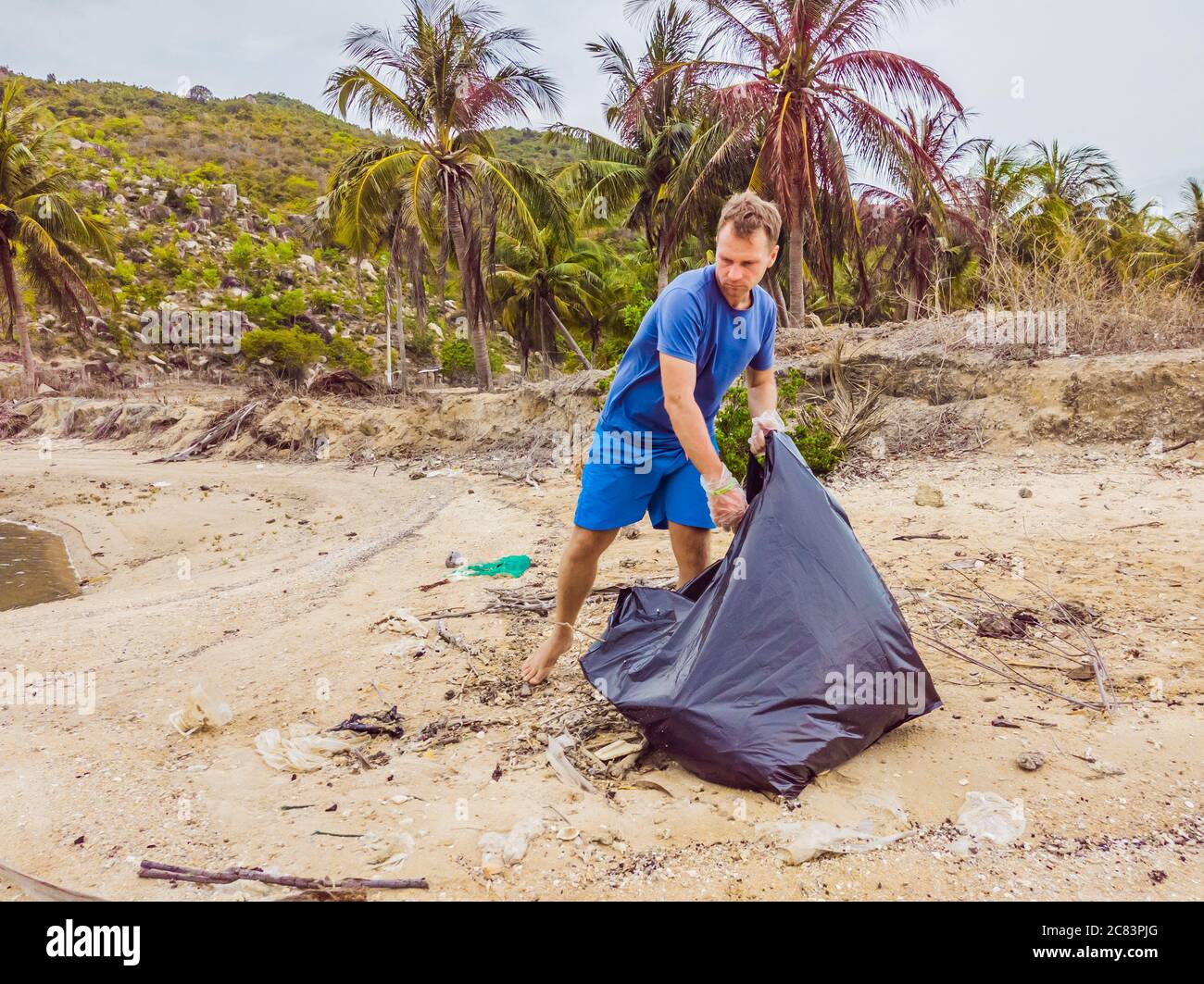 Man in gloves pick up plastic bags that pollute sea. Problem of spilled ...