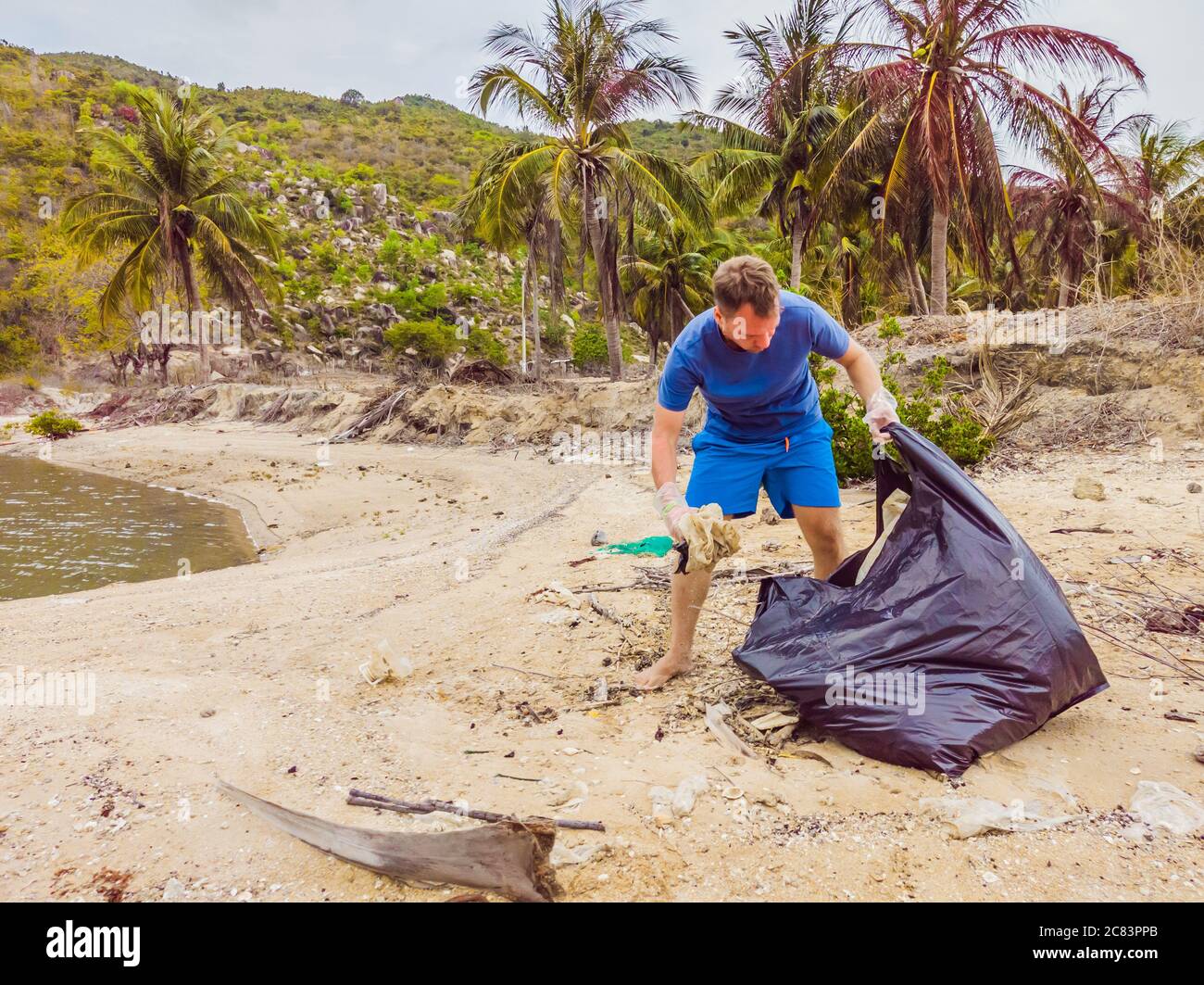 Man in gloves pick up plastic bags that pollute sea. Problem of spilled ...