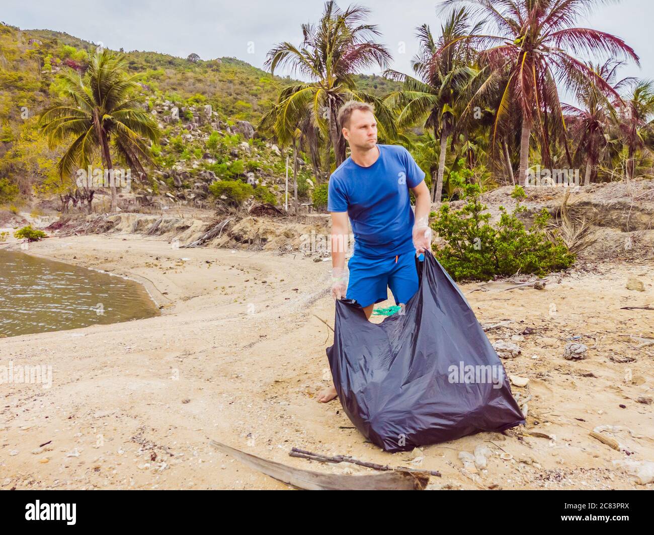 Man in gloves pick up plastic bags that pollute sea. Problem of spilled ...