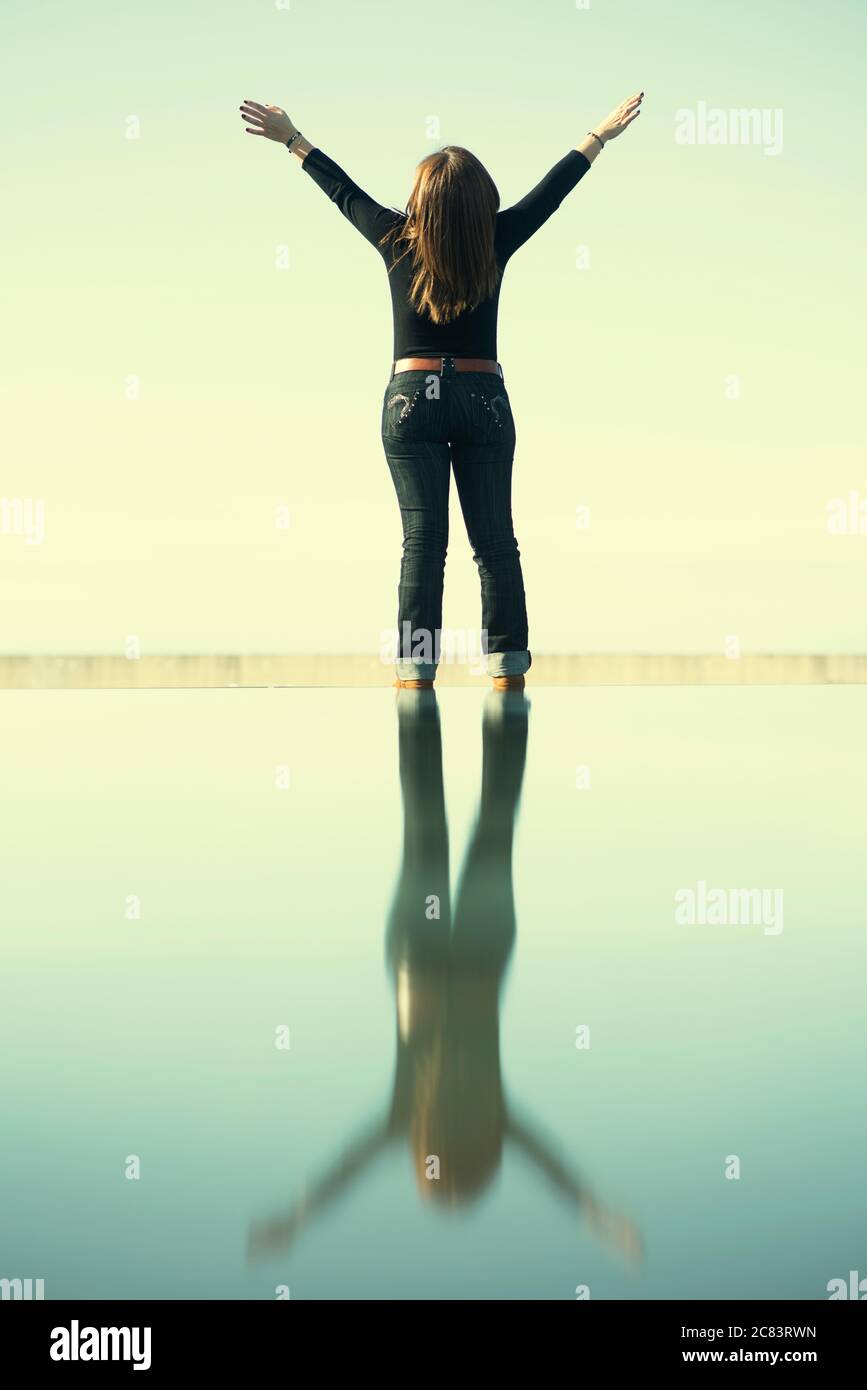 Rear view of woman arms outstretched Stock Photo - Alamy