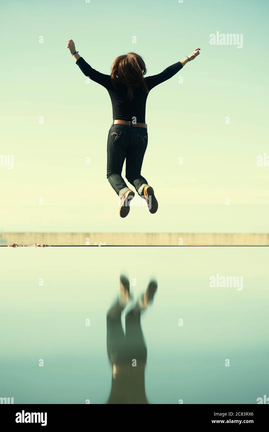 Rear view of woman jumping Stock Photo - Alamy