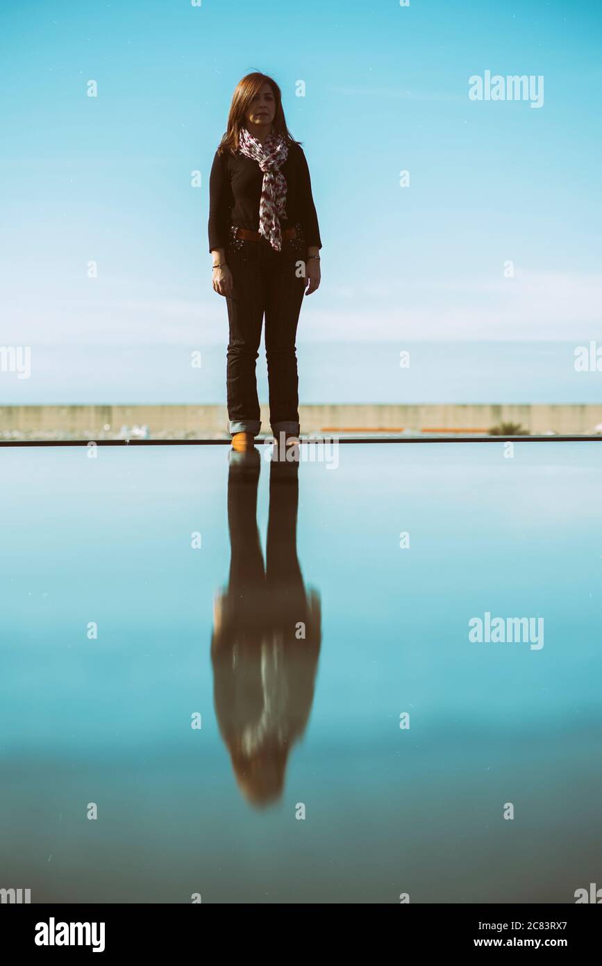 Woman standing outdoors with reflection on water Stock Photo - Alamy