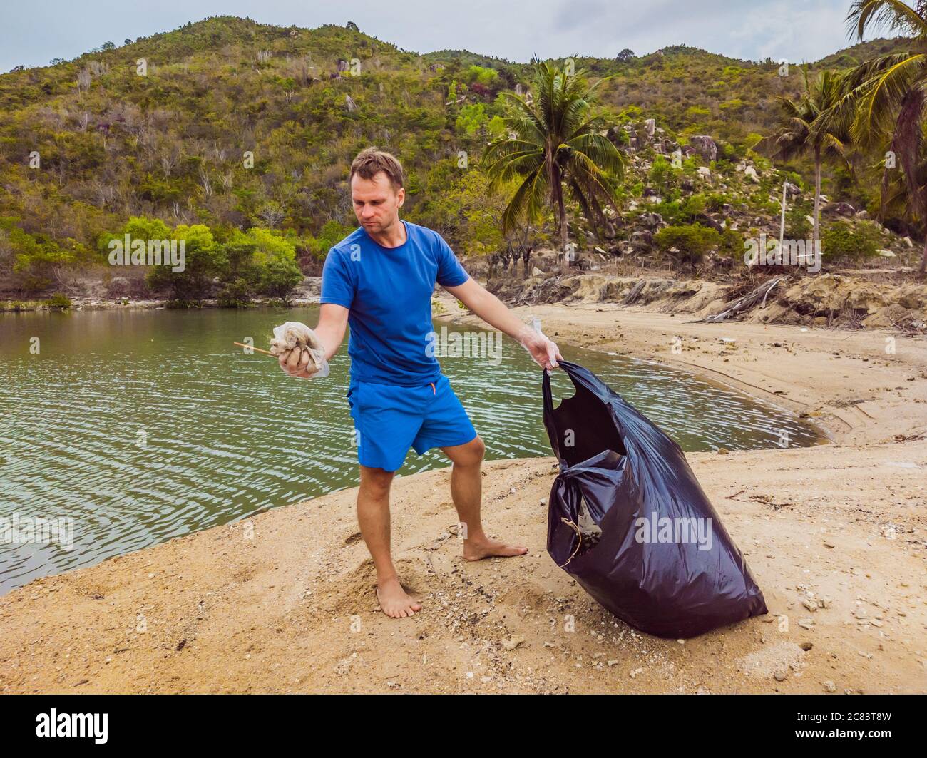 Man in gloves pick up plastic bags that pollute sea. Problem of spilled ...