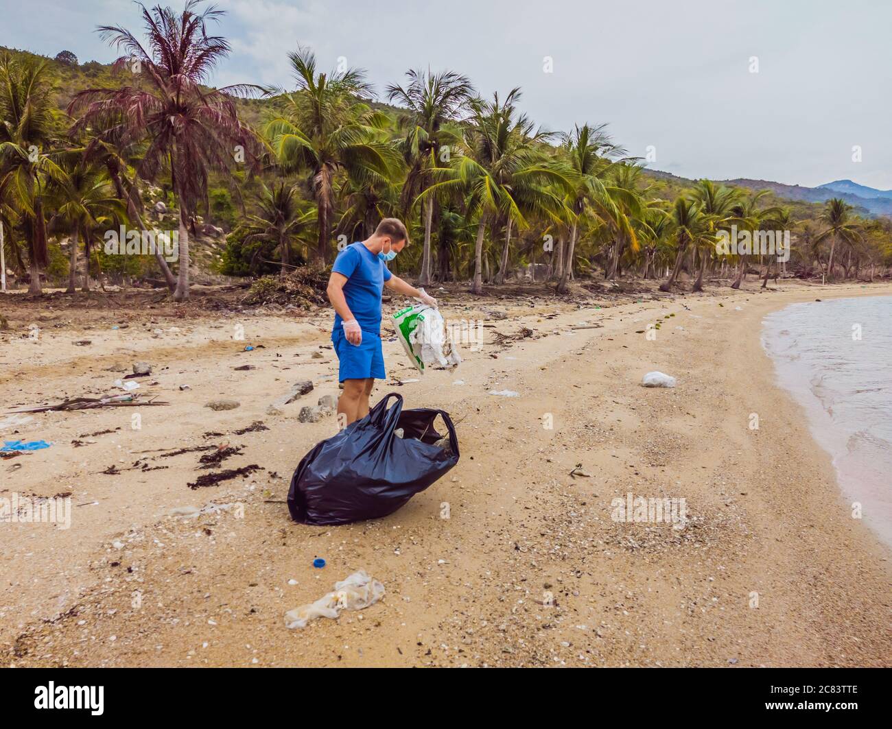 Man in gloves pick up plastic bags that pollute sea. Problem of spilled ...