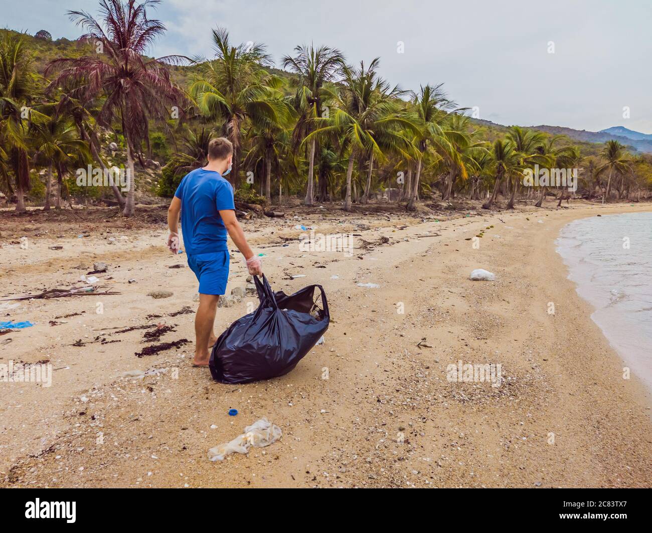 Man in gloves pick up plastic bags that pollute sea. Problem of spilled ...